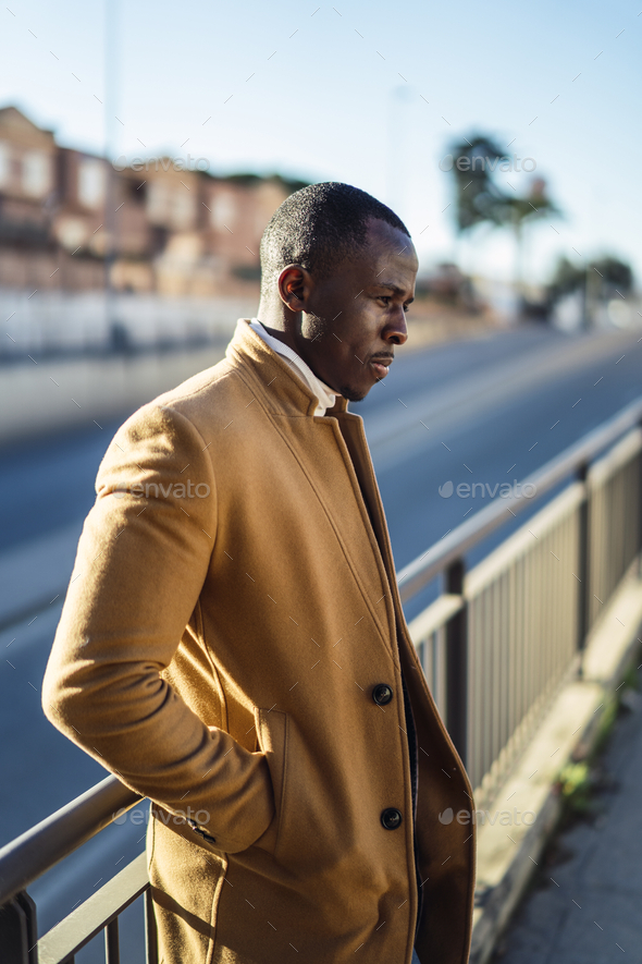 Shallow focus shot of a stylish handsome African male in a coat posing ...