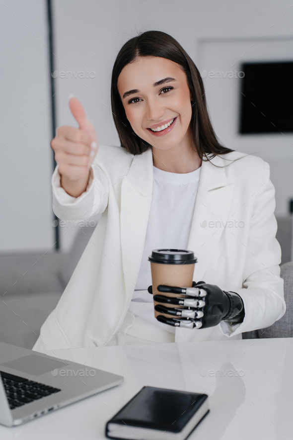 Girl with disability in white suite with bionic hand prosthesis, holds ...