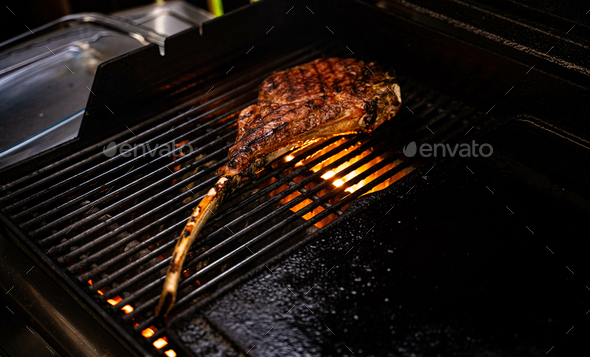Steak getting cooked on a grill in a kitchen Stock Photo by wirestock