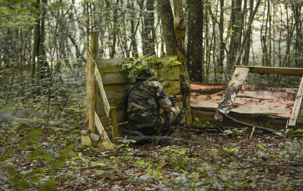 Back view of special forces soldier hiding behind a wooden fence in a ...