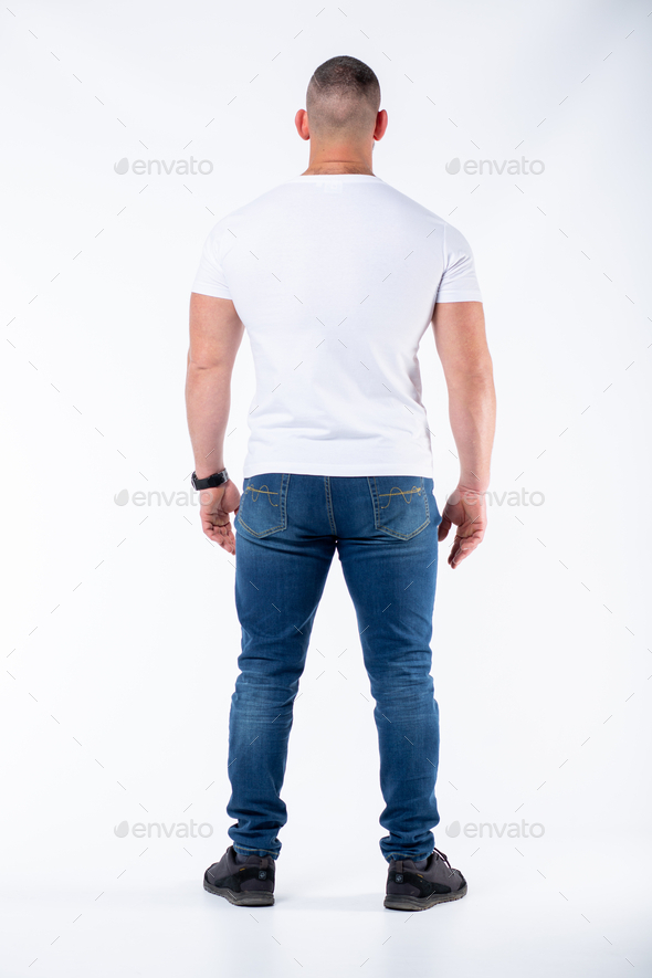 Rear view of a manstanding while wearing a white t-shirt and a pair of ...