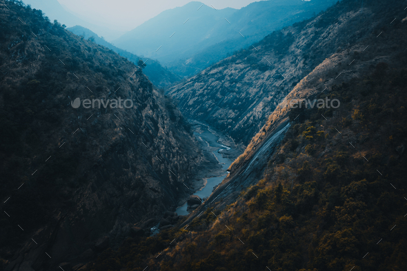 Eerie scenery of a river flowing in the valley between high mountains ...