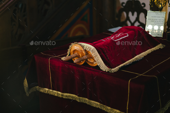 Torah Scrolls on the table covered with red cloth and paper with Hebrew ...