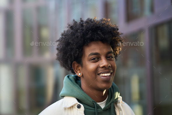 Smiling young gen z African American teen standing at city street ...
