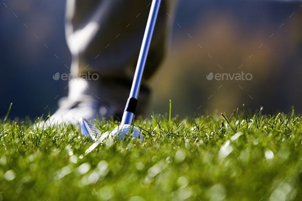 Selective focus of a ball and club in a golf course against a blurred ...