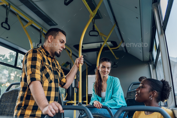 Multiracial friends talking while riding a bus in the city Stock Photo ...