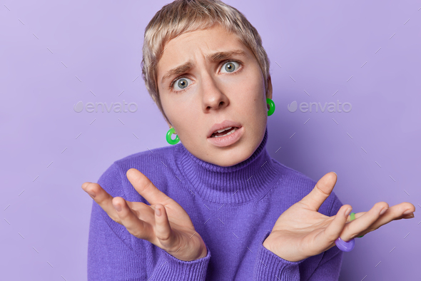 Portrait of confused shocked young woman with short hairstyle spreads ...