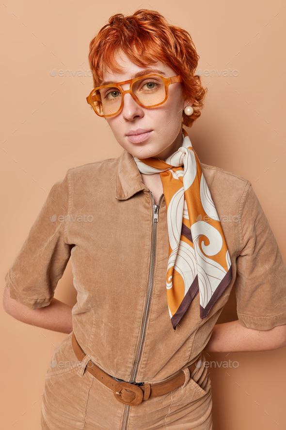 Vertical shot of calm serious female model with red hair keeps hands ...