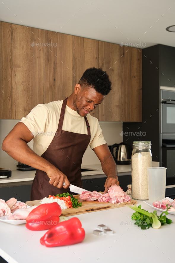 Young black man de-boning chicken to prepare a recipe. Stock Photo by ...