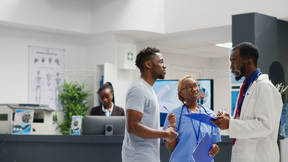 Medic and nurse discussing about treatment with male patient Stock ...