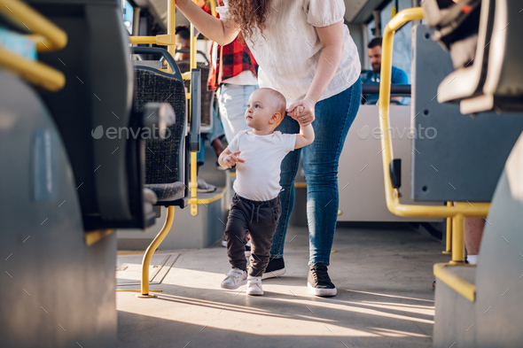Mother and child standing in moving bus Stock Photo by zamrznutitonovi