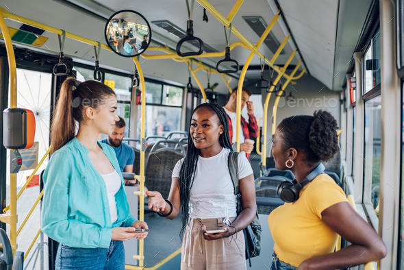 Multiracial friends talking while riding a bus in the city Stock Photo ...