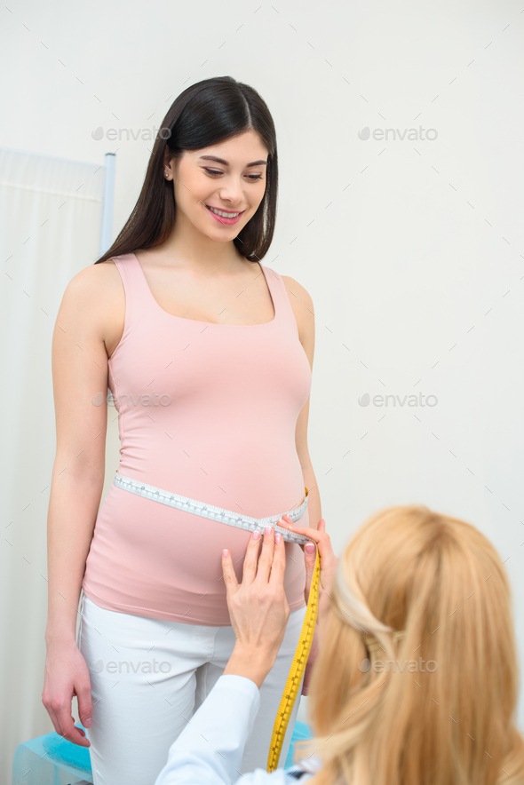 obstetrician gynecologist measuring belly size of young pregnant woman ...