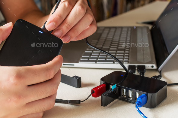 Male hand connecting the hard drive with a USB cable to a laptop ...