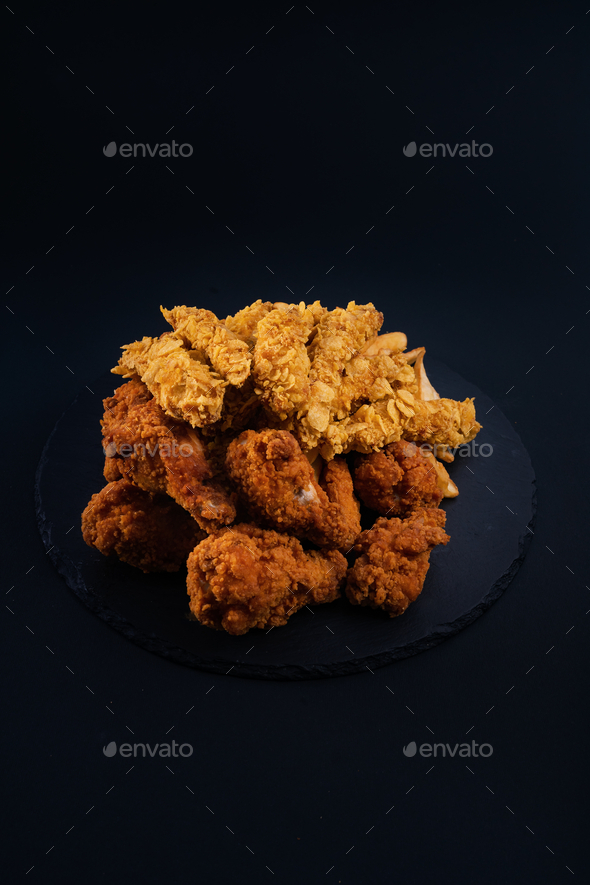 Closeup shot of a black serving plate full of chicken nuggets and ...