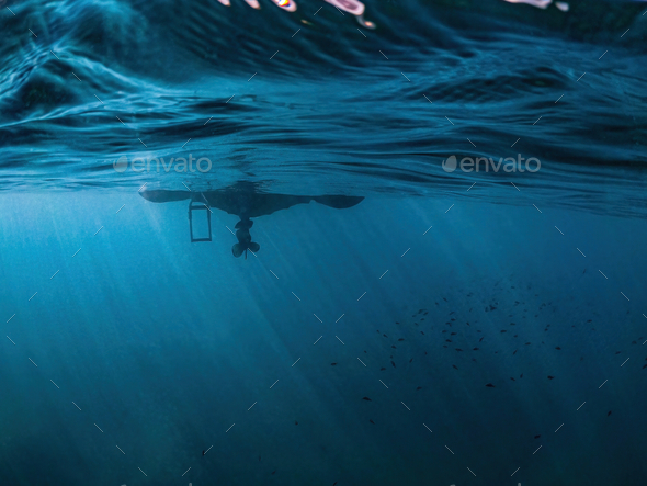 Underwater view of a boat bottom part and fishes swimming in clear blue ...
