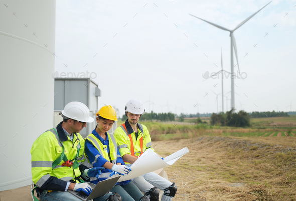 Wide perspective of wind turbine engineers walking with coworker in ...