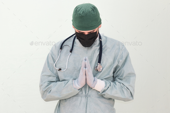 Male doctor praying for a surgery to go well Stock Photo by wirestock