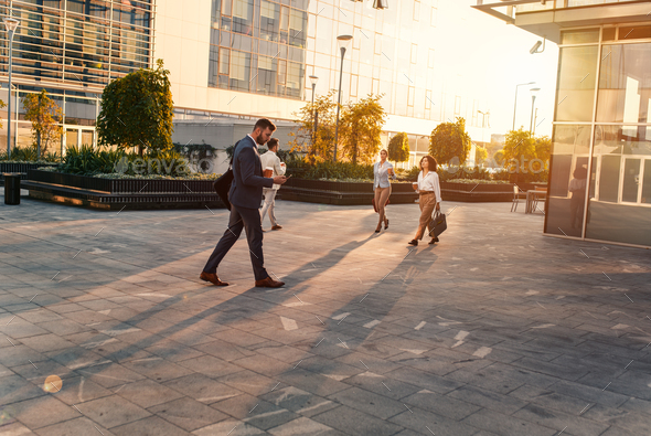 Group of business people walking outside in front of office buildings ...