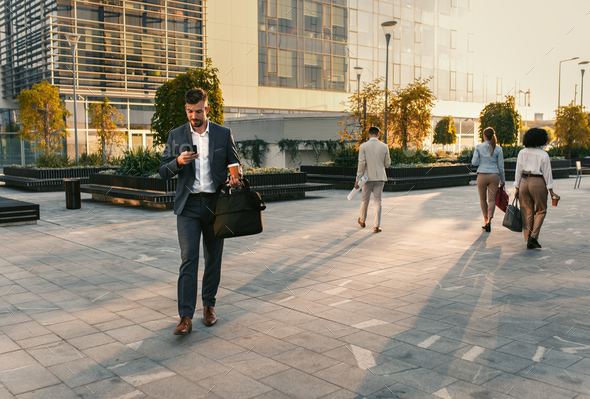 Group of business people walking outside in front of office buildings ...