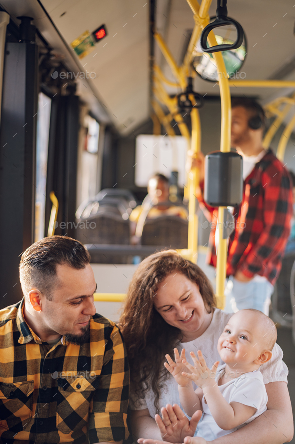 Happy parents and son riding in bus while baby sits in mother lap ...