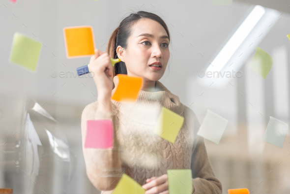 Business Asian woman meeting at office and use post it notes in glass ...