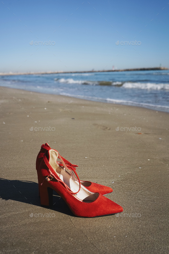 Red high heels with retro style abandoned in a seashore near the sea ...