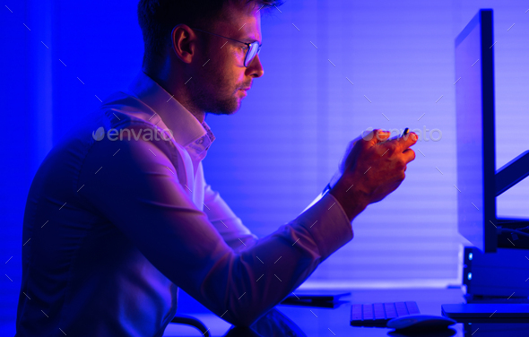 Man Browsing His Smartphone Apps in Front of Desktop Computer Stock ...