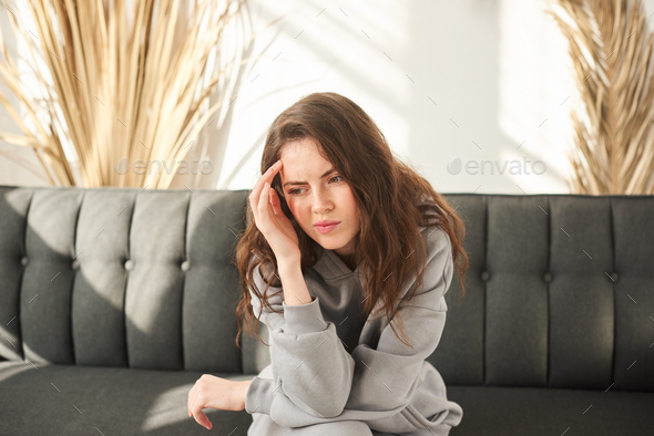 bored and sad woman sitting on couch with no mood and prop up head with ...