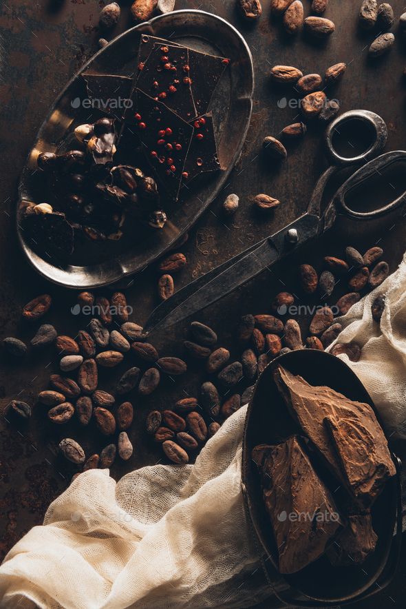 vintage scissors, cocoa beans, cloth, chocolate pieces and nuts on dark ...