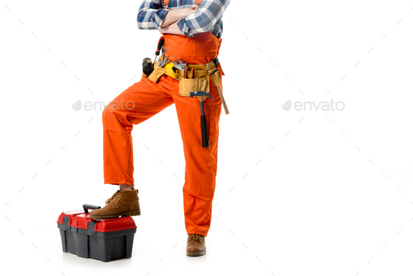 Cropped view of workman in orange overall leaning on tool box isolated ...