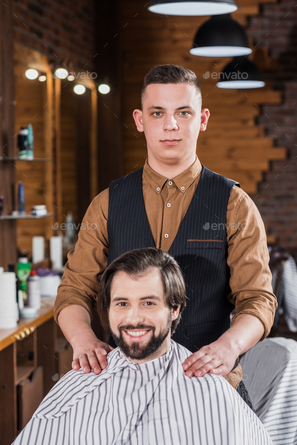 handsome young barber standing behind client at workplace Stock Photo ...