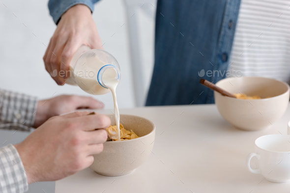 pouring milk into corn flakes, young couple having breakfast Stock ...