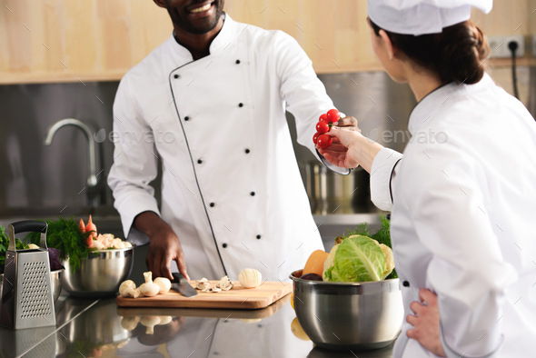 Multiracial team of cooks sharing cooking ingredients Stock Photo by ...