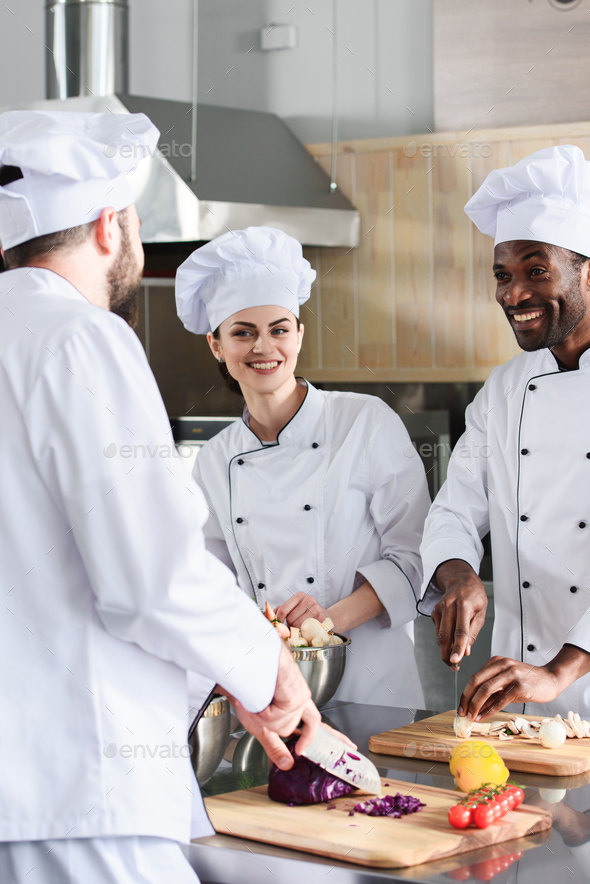 Multiracial chefs team smiling and cooking on modern kitchen Stock ...