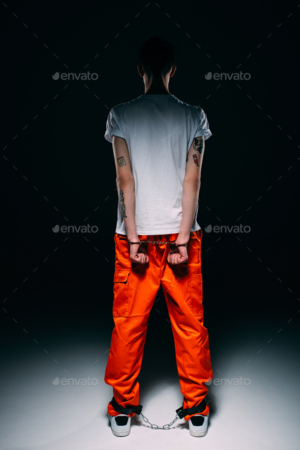 Rear view of man wearing prison uniform with hands cuffed behind his ...