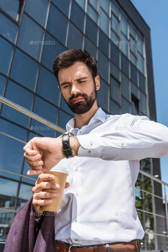 bottom view of handsome young businessman with coffee to go looking at ...