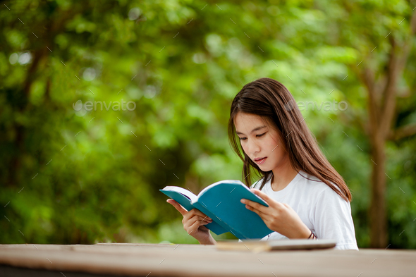 Asian girl reading book at park in summer sunset light. asian woman ...