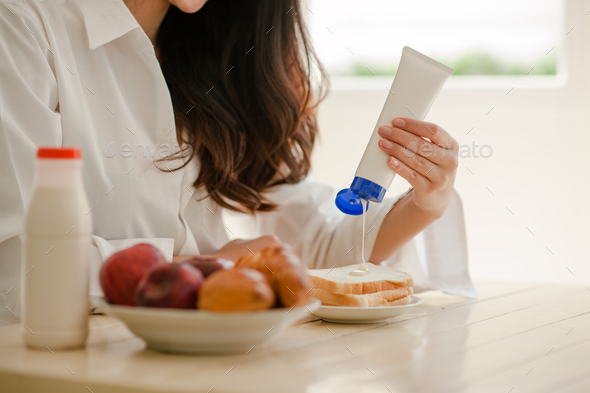 Close Up of woman's hand squeezing sweetened condensed milk into bread ...