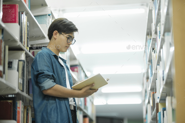 Student reading book at library. Stock Photo by ijeab | PhotoDune
