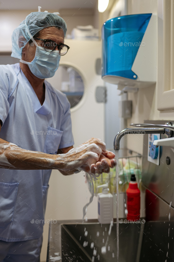 doctor washing his hands in the operating room. Stock Photo by karrastock