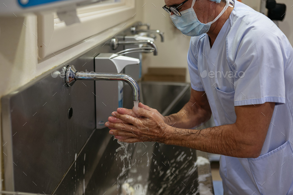 doctor washing his hands in the operating room. Stock Photo by karrastock