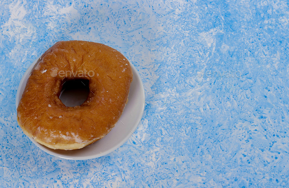 Top view closeup of a fresh doughnut on a small white plate with a ...