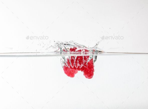 Raspberry in water on a white background with water sprays around, can ...