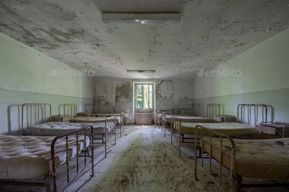 Old abandoned and dilapidated hospital with many beds with windows in ...