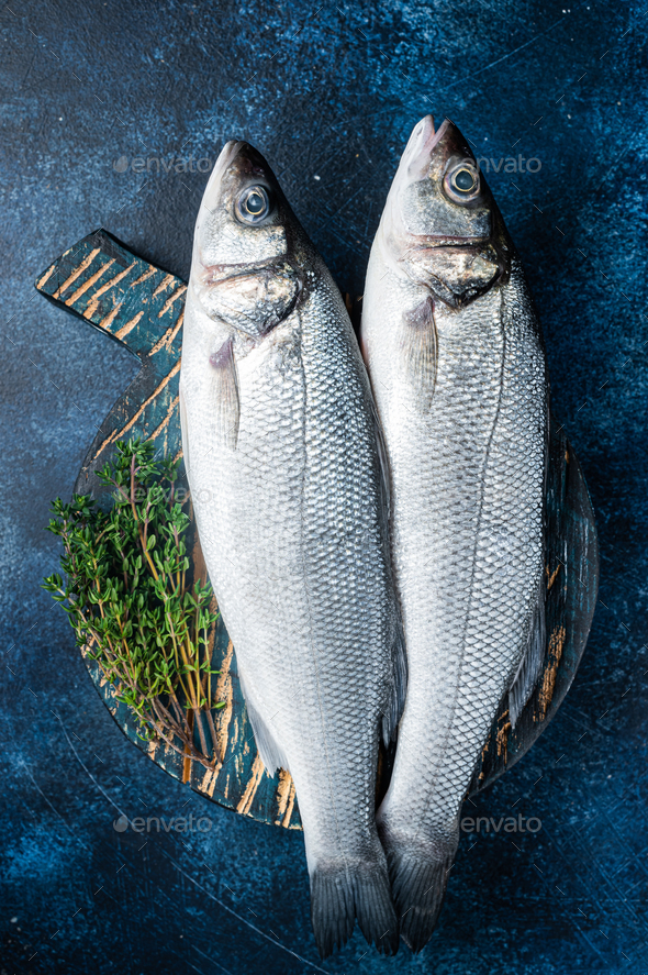 Uncooked Raw Sea Bass fish, Seabass with thyme. Blue background. Top ...