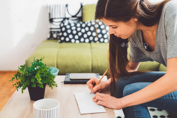 Young caucasian woman sending a letter, writing the address on it Stock ...