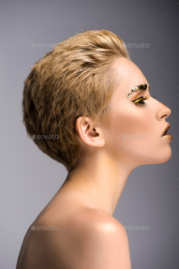 side view of attractive woman with golden glitter on face and short ...