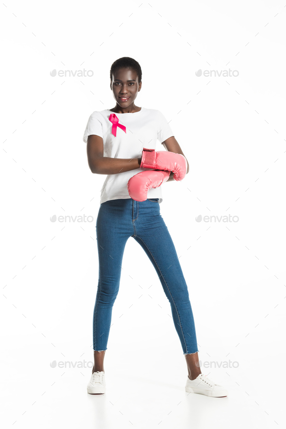 full length view of young woman with pink ribbon wearing boxing gloves ...