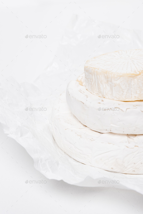 stack of delicious brie cheese heads on crumpled paper and on white ...